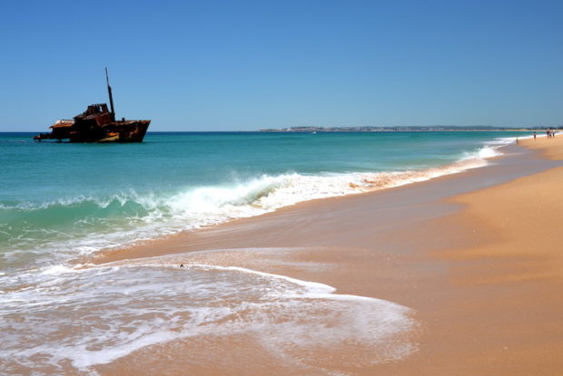 Horizontal landscape of the beach with a fisherman, shipwreck in the ...
